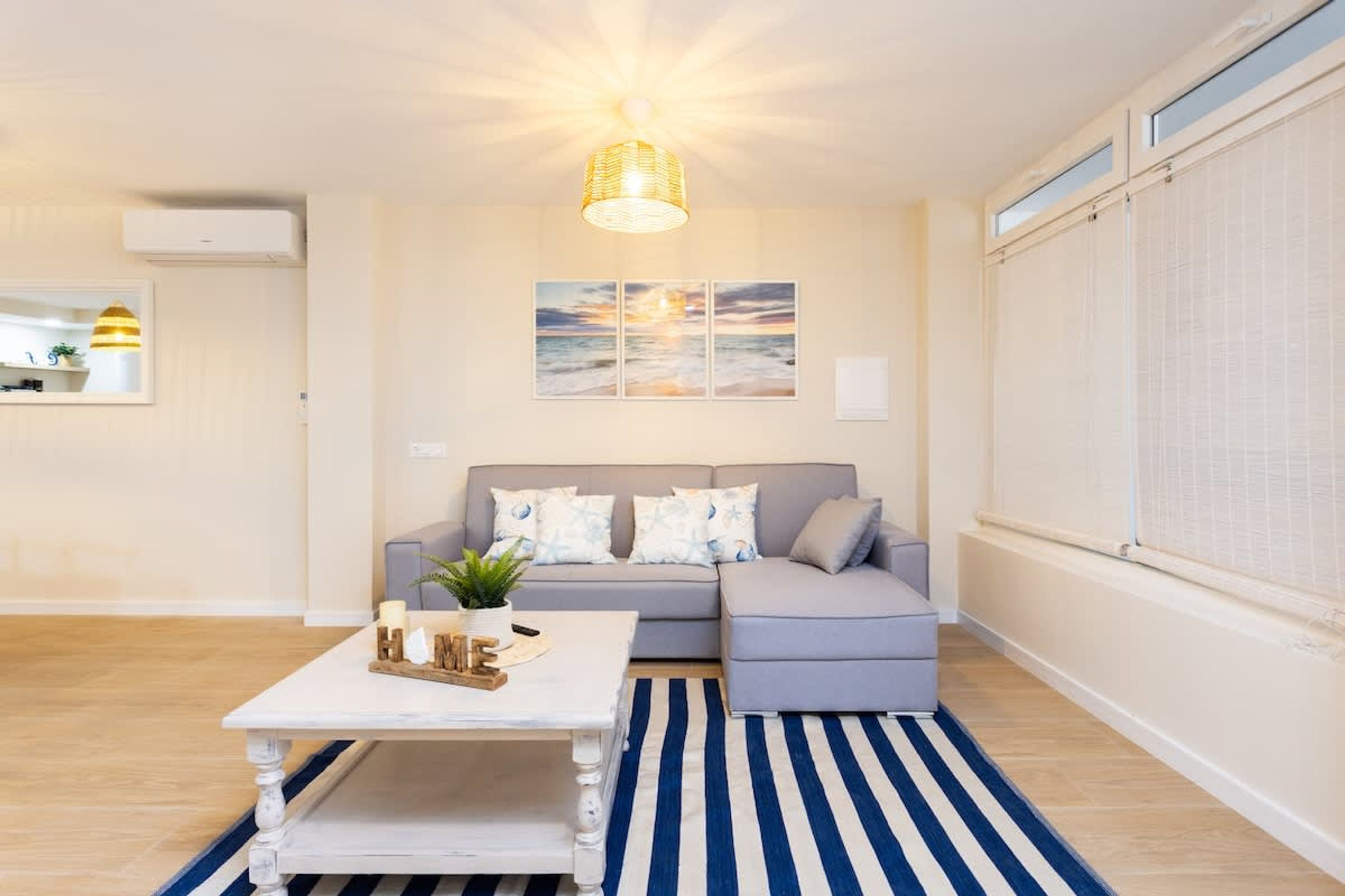 Sala de estar com sofá, mesa de centro, luminária pendente e um quadro na parede.