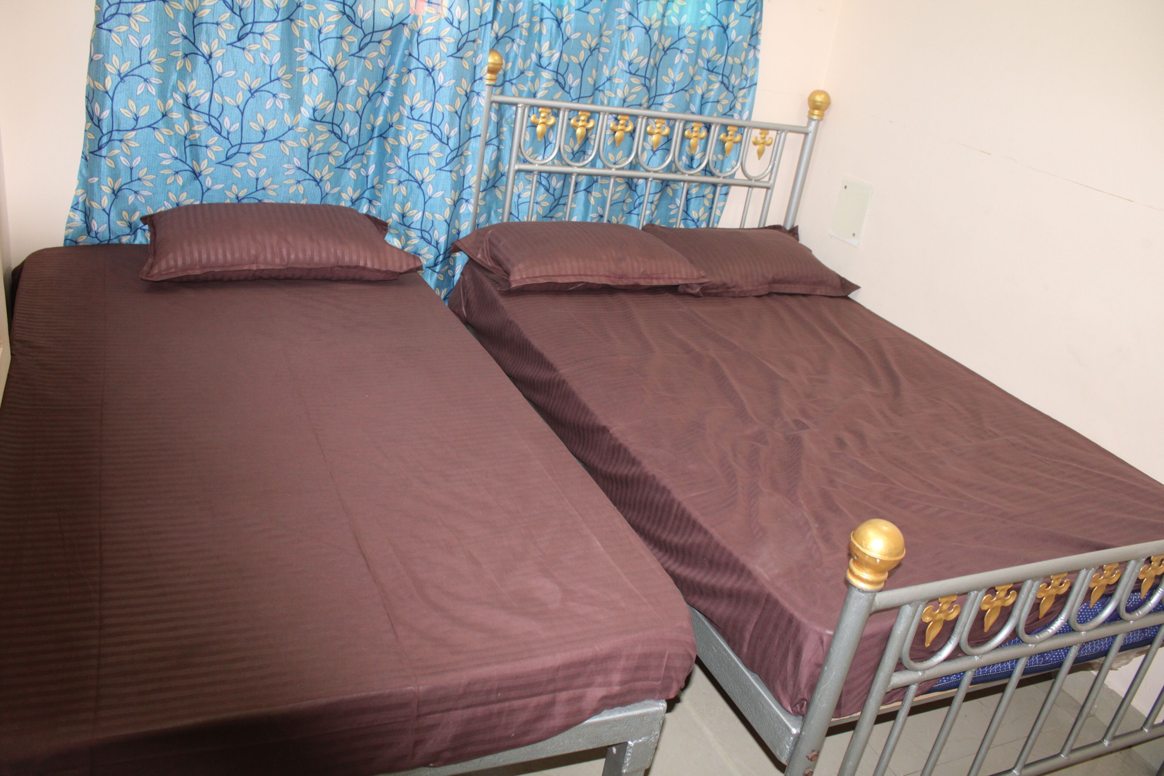 Uma cama de casal com estrutura metálica e cabeceira com detalhes decorativos.