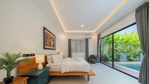 Quarto moderno com cama, mesa de cabeceira, luminária, planta em vaso e vista para uma piscina.
