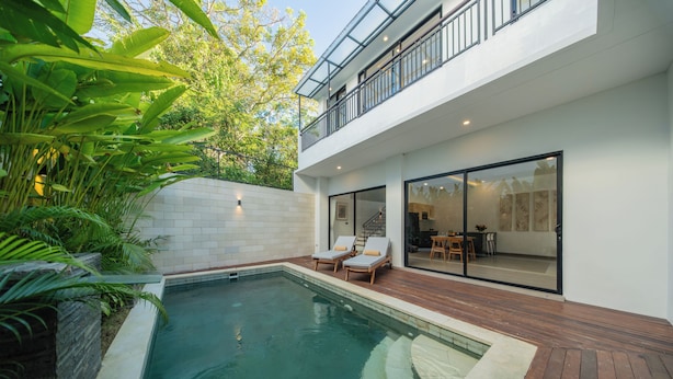 Uma casa moderna com piscina, deck de madeira e varanda.