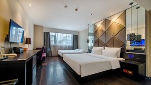 Quarto de hotel com duas camas, uma escrivaninha com um computador, uma televisão e um espelho grande.