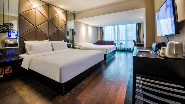 Quarto de hotel com cama grande, escrivaninha, televisão e vista da cidade.