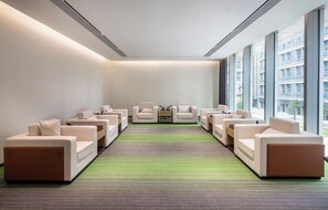 Uma sala de conferências com uma mesa comprida, várias cadeiras e janelas amplas.