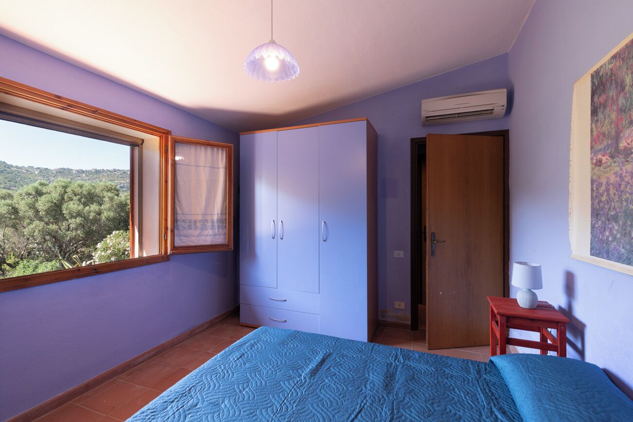 Quarto com cama, guarda-roupa, janela e ar condicionado.