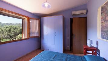 Quarto com cama, guarda-roupa, janela e ar condicionado.