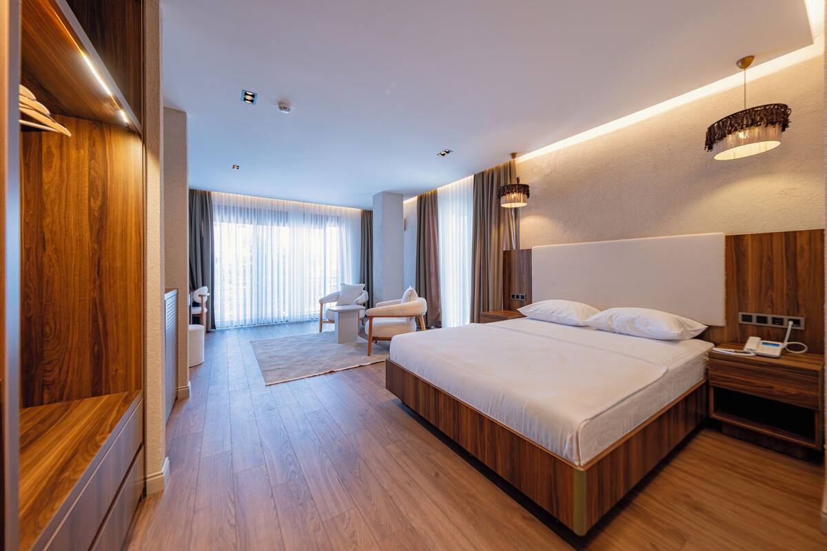 Quarto de hotel moderno com uma cama grande, mesas de cabeceira, uma escrivaninha e uma cadeira.