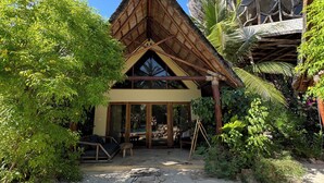 Um edifício com telhado de palha, uma janela grande e um deck de madeira.