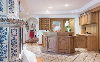 Uma cozinha com armários de madeira, piso ladrilhado e uma parede decorativa com padrões azuis.