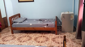 Uma cama de solteiro com estrutura de madeira, uma pequena mesa de cabeceira, uma televisão na parede e um chão com padrão.