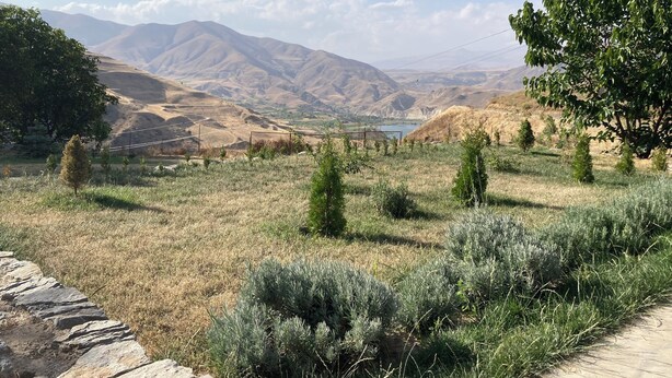 Paisagem montanhosa com céu claro, um corpo d'água e vegetação escassa.