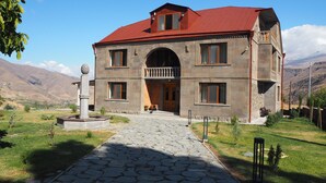 Um edifício de dois andares com telhado vermelho, fachada de pedra e uma entrada central com varanda.