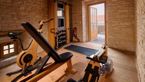 Uma academia com equipamentos de ginástica, parede de pedra e teto de madeira.