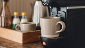 Uma máquina de café com uma chávena de café sobre um tabuleiro.