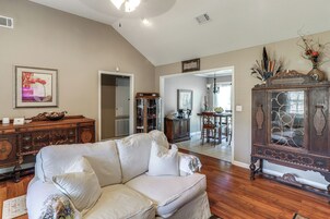 Uma sala de estar com um sofá, um aparador de madeira e uma área de jantar ao fundo.