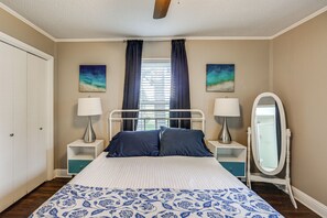 Quarto com cama, duas mesas de cabeceira, cômoda, espelho e obras de arte nas paredes.