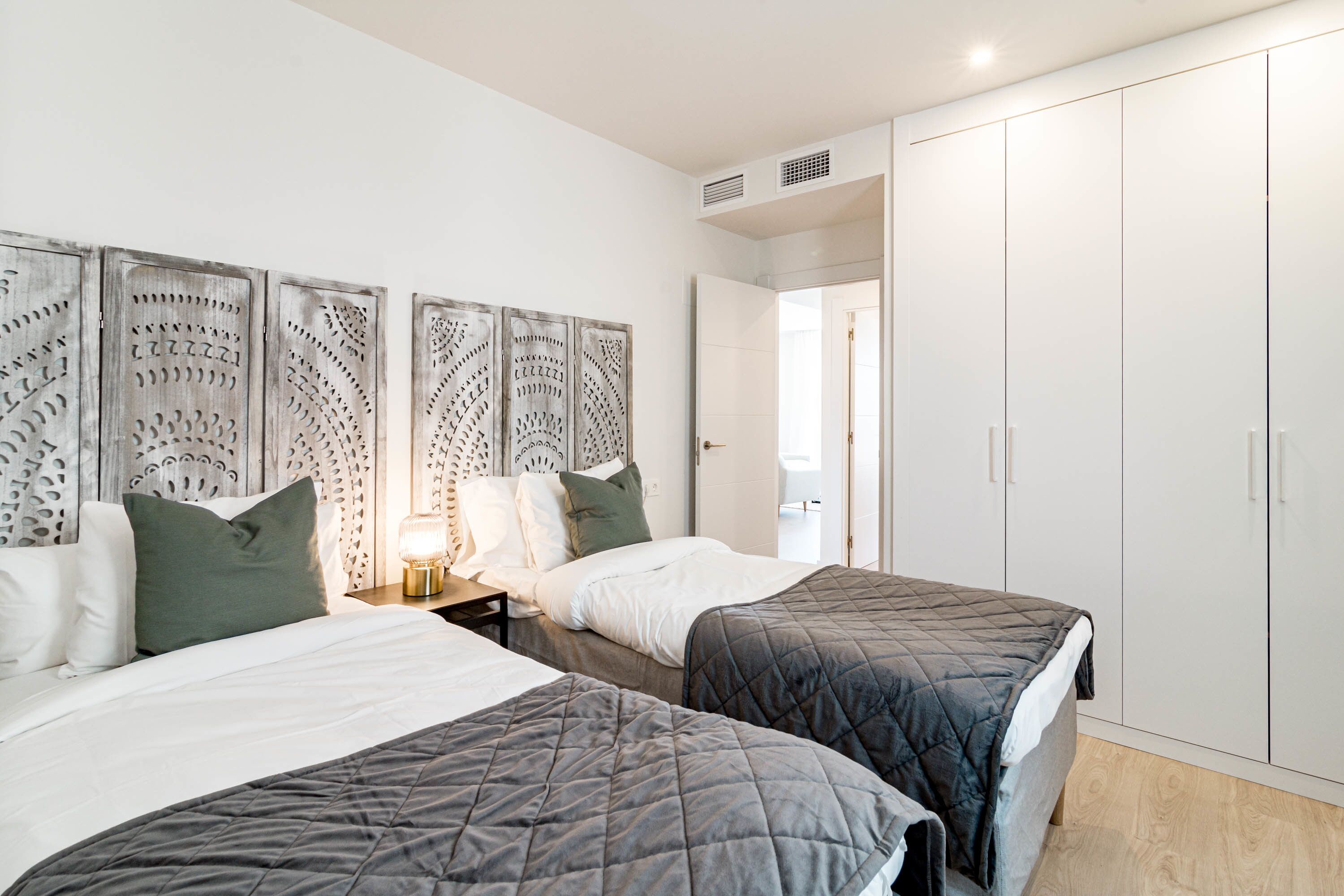 Quarto com duas camas, guarda-roupa e painéis decorativos na parede.