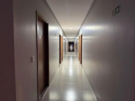Um corredor comprido e estreito, com portas de ambos os lados, conduzindo a uma saída distante.