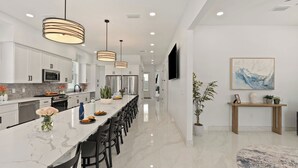 Cozinha moderna com armários brancos, bancada de mármore e eletrodomésticos de aço inoxidável.