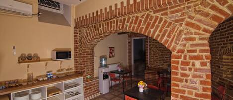 Uma cozinha com arco de tijolos, geladeira, micro-ondas e área de jantar com cadeiras e mesa.