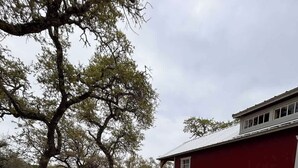 Um edifício vermelho com acesso por um caminho de brita e árvores.