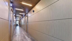 Um corredor longo e estreito, com piso estampado e painéis de madeira nas paredes.