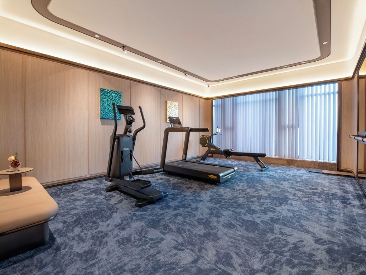 Quarto de hotel com esteira ergométrica, bicicleta ergométrica e cadeira de massagem.