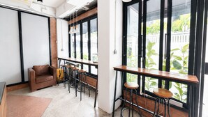 Um interior moderno com sofá, banquetas de bar e uma janela com vista para o verde.
