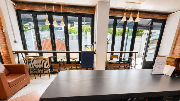 Uma área de bar moderna com um balcão comprido, banquetas e luminárias pendentes.