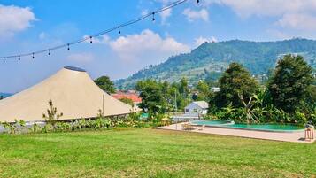 Uma estrutura em forma de tenda, uma piscina e uma paisagem montanhosa ao fundo.