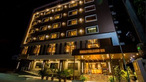 Um hotel com vários andares, janelas iluminadas e uma área de recepção.