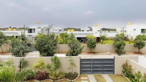 Um bairro residencial com casas modernas, uma entrada com portão e bastante vegetação.