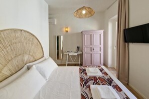 Quarto com uma cama, guarda-roupa, escrivaninha, espelho e televisão.