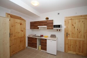 Cozinha compacta com armários de madeira, micro-ondas, torradeira e uma pia pequena.
