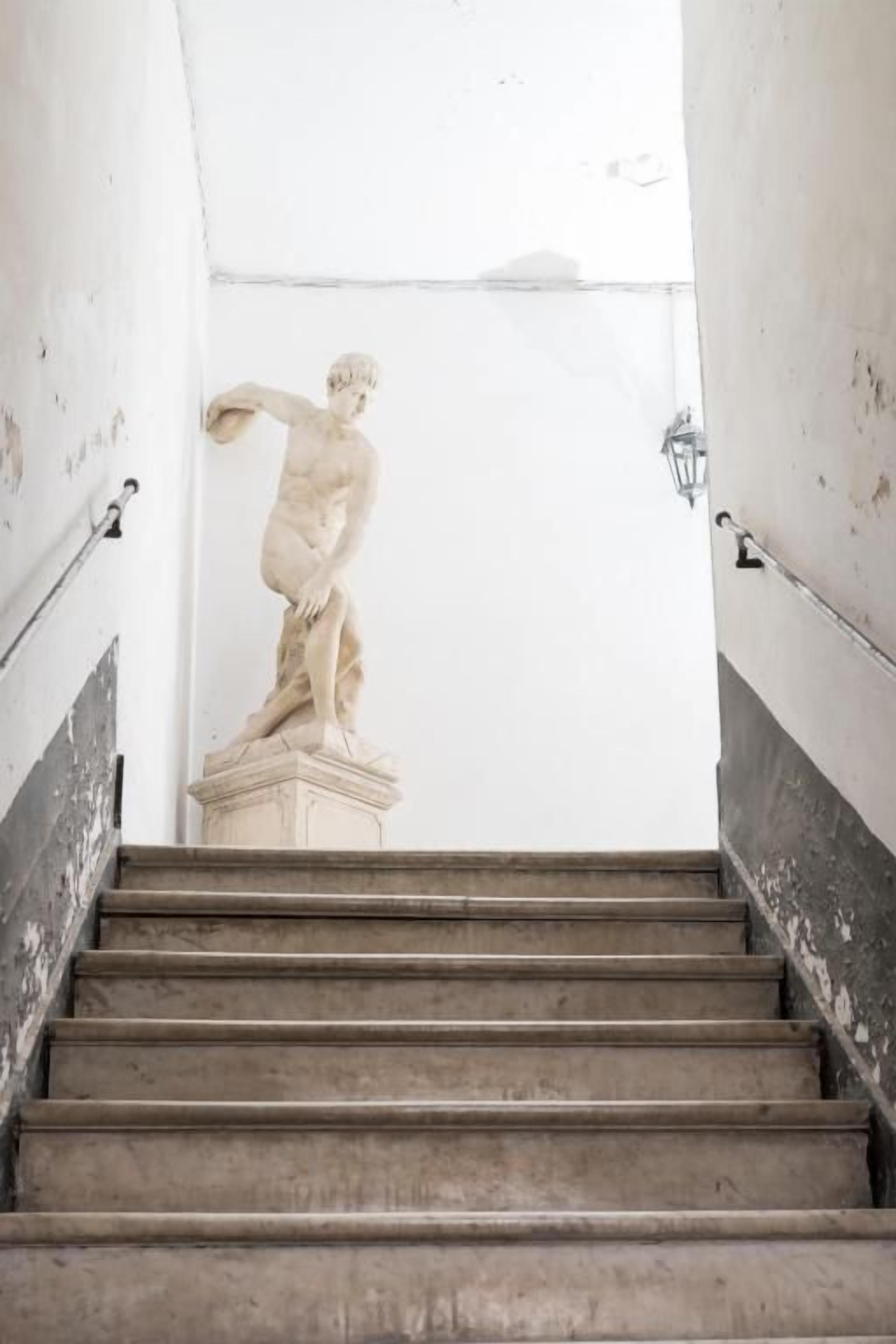 Uma escadaria com uma estátua clássica no topo.