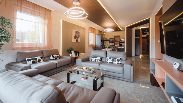 Uma sala de estar moderna, com sofás, mesa de centro e iluminação pendente.