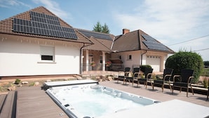 Uma casa com hidromassagem, painéis solares e mobiliário de exterior.