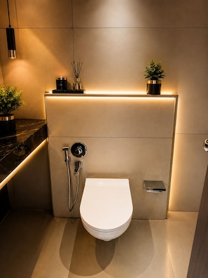 Um banheiro moderno com vaso sanitário branco, chuveiro e área de pia com planta e velas.