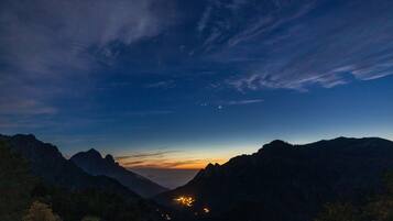 Paisagem montanhosa ao crepúsculo, com uma povoação visível no vale.