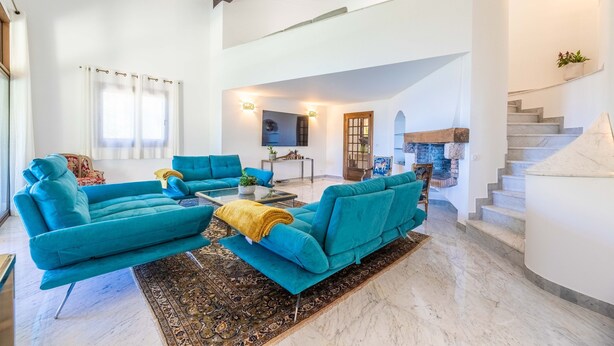 Uma sala de estar espaçosa, com teto alto, escada e lareira.