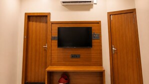 Uma sala de estar moderna com uma televisão de tela plana montada em uma parede de madeira, um ventilador de teto e um ar-condicionado.