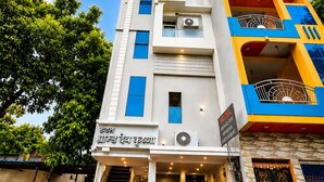 Um hotel com uma escadaria que leva à entrada, uma placa com texto e um edifício de vários andares com sacadas.