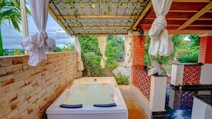 Uma área de spa com hidromassagem, parede de tijolos e vista para o verde.