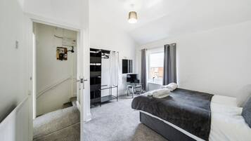 Um quarto com cama, escrivaninha, cadeira e guarda-roupa.