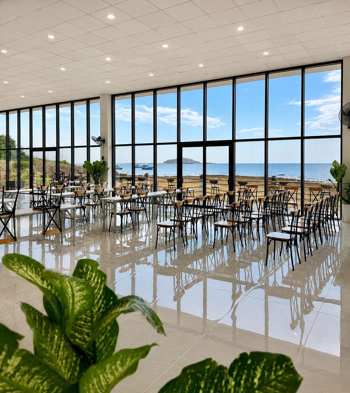 Uma ampla área de refeições interna com grandes janelas com vista para uma praia.