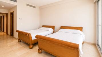 Quarto de hotel com duas camas de madeira, um corredor e uma janela.