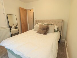 Quarto com cama, espelho, porta e radiador.