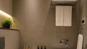 Uma casa de banho moderna com sanita branca, lavatório suspenso e chuveiro.