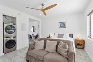 Quarto moderno com cama, ventilador de teto, máquina de lavar e sofá.