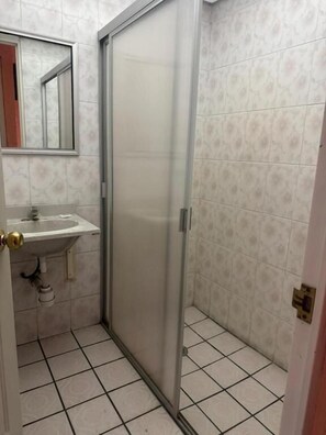 Um banheiro com box de vidro, pia e paredes revestidas de azulejos.