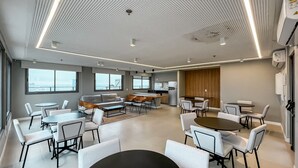 Um interior moderno com área de refeições, cozinha e assentos.
